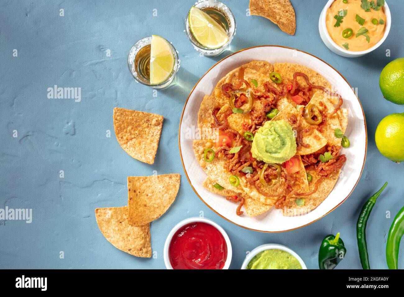 Nachos, shot from above with tequila and copy space on a blue ...
