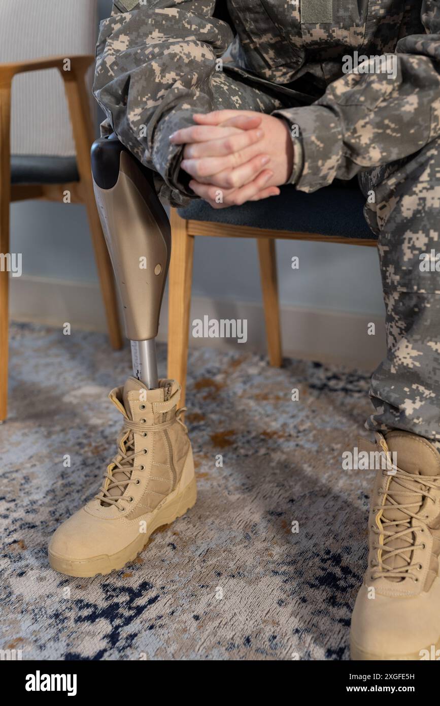 Sitting in uniform, soldier with prosthetic leg resting hands on lap ...