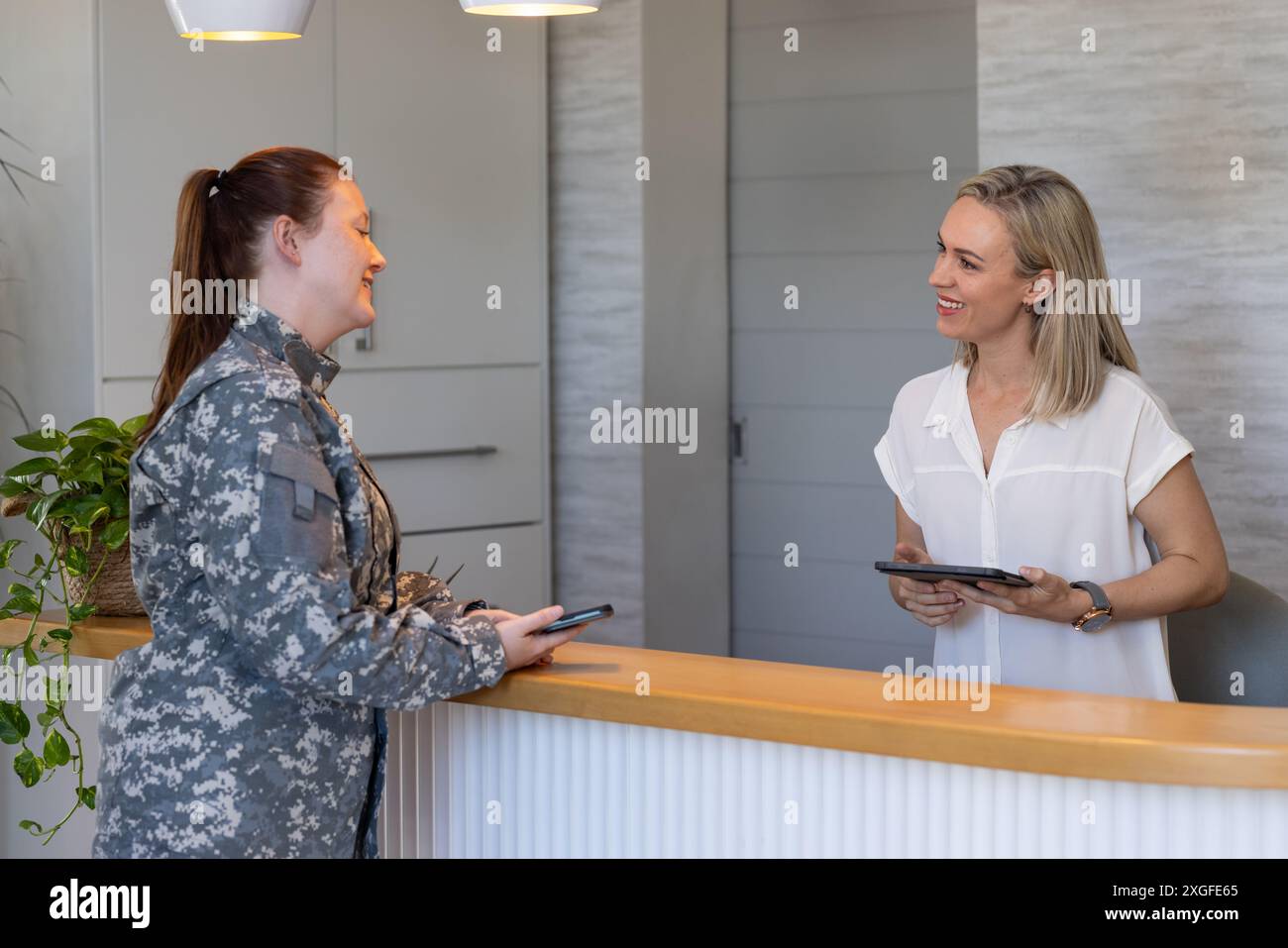 Military soldier woman talking to receptionist holding tablet at ...