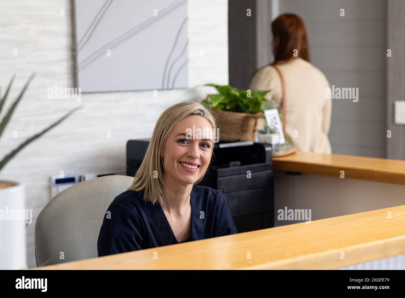 Welcoming patients, smiling receptionist at medical clinic front desk ...