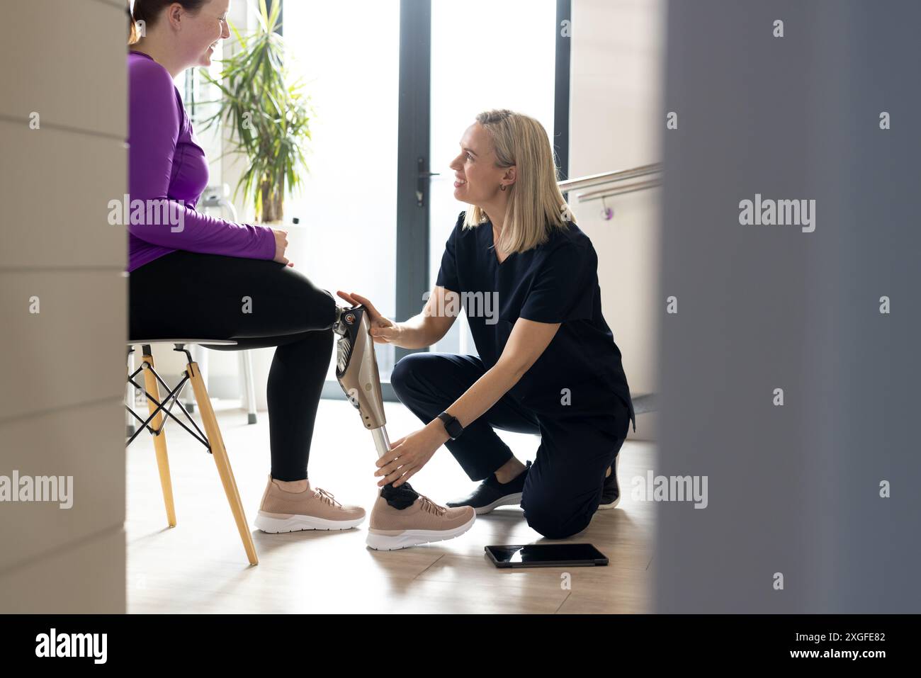 Fitting prosthetic leg, woman assisting patient in modern medical ...