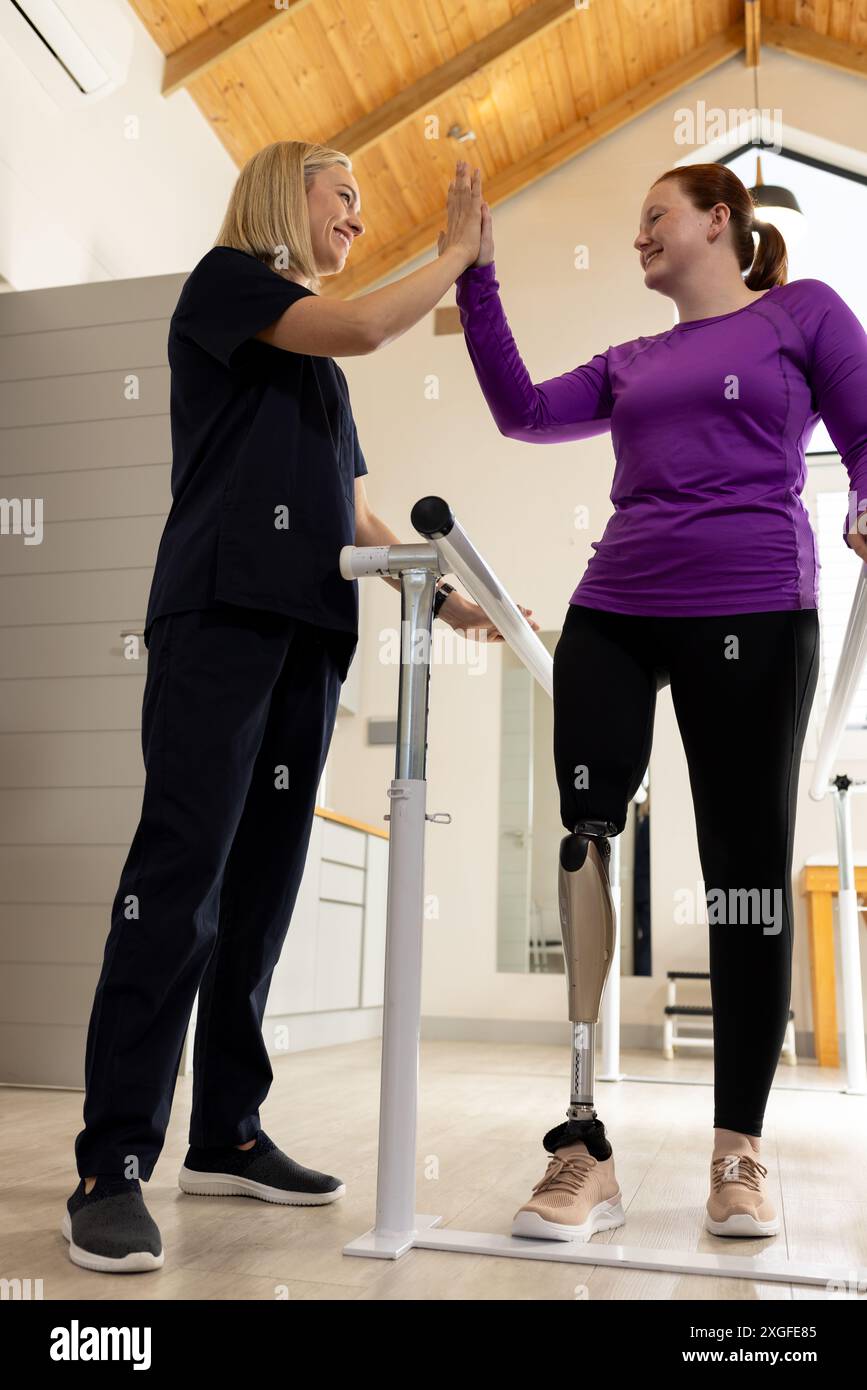 Therapist and woman with prosthetic leg high-fiving during ...
