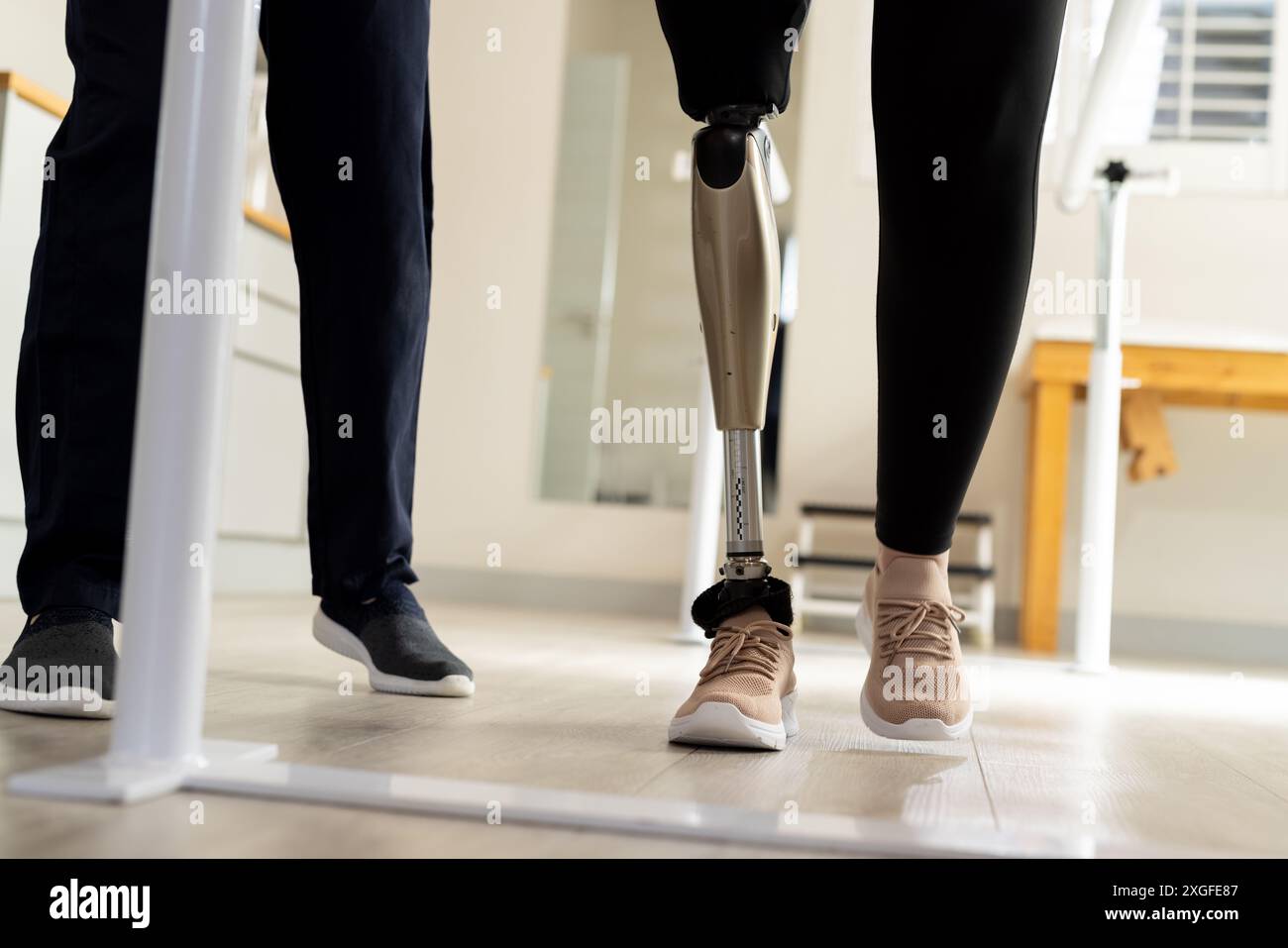 Walking with prosthetic leg, person receiving support from therapist in ...