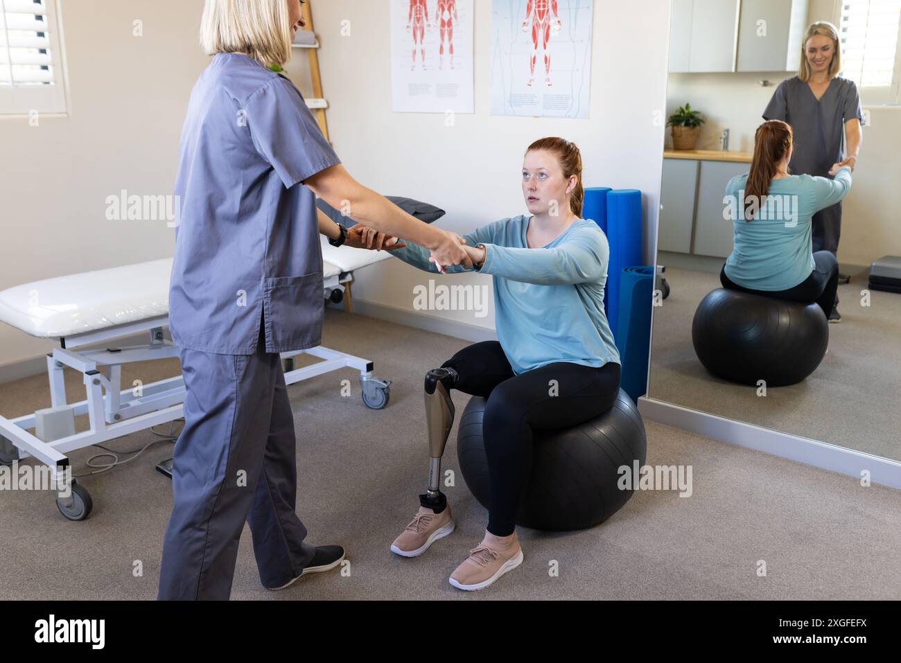 Balancing on exercise ball, woman with prosthetic leg assisted by ...
