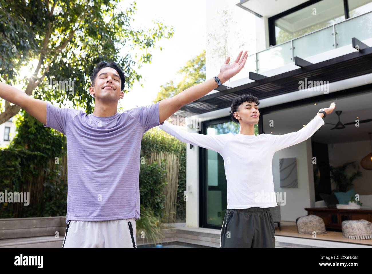 Practicing outdoor yoga, male gay couple stretching arms in backyard garden Stock Photo - Alamy