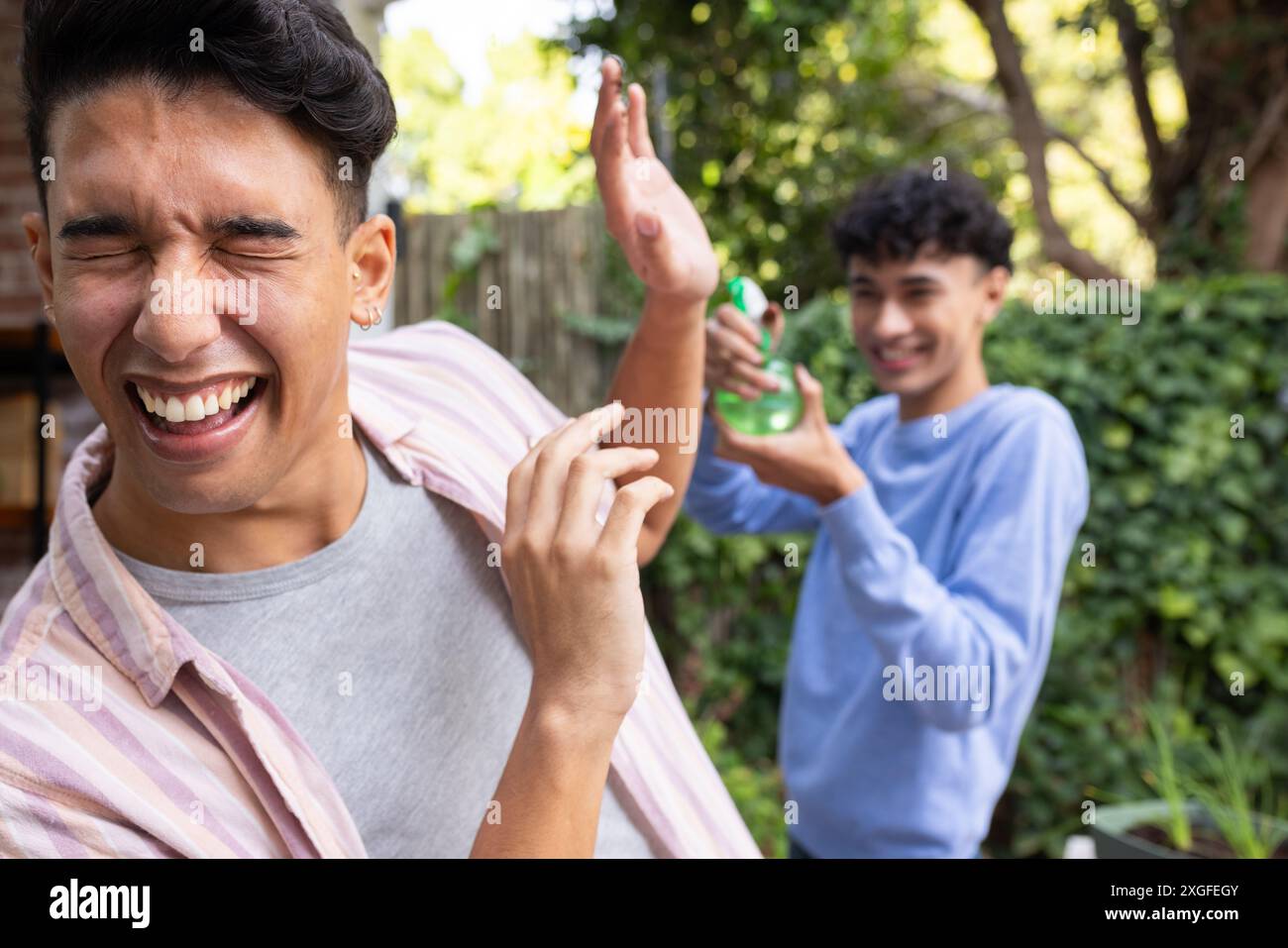 Laughing and spraying water, playful male gay couple enjoying outdoor ...