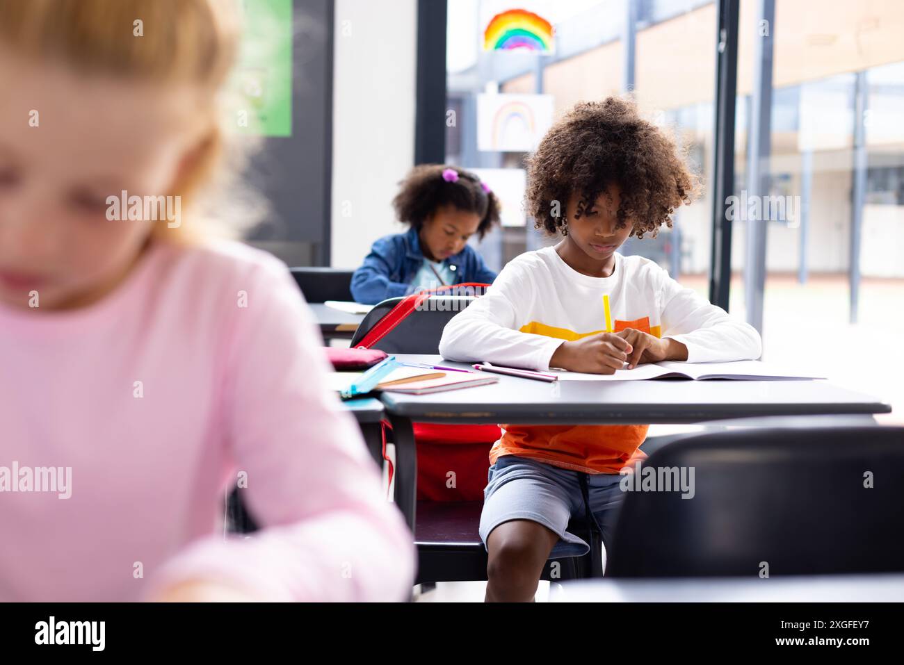 Happy diverse schoolchildren sitting at desks in school classroom Stock ...