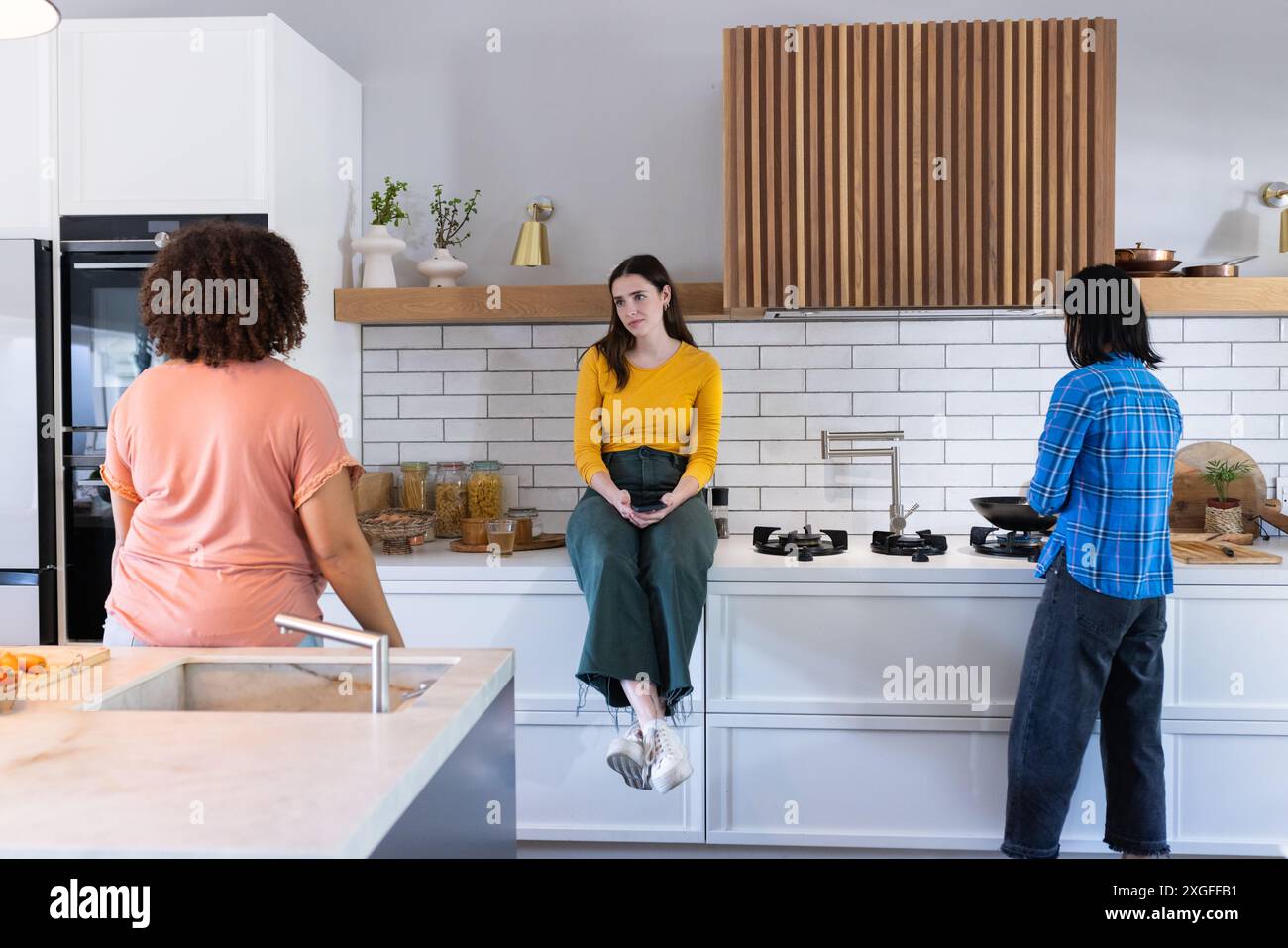 Talking in kitchen, three women friends having casual conversation ...