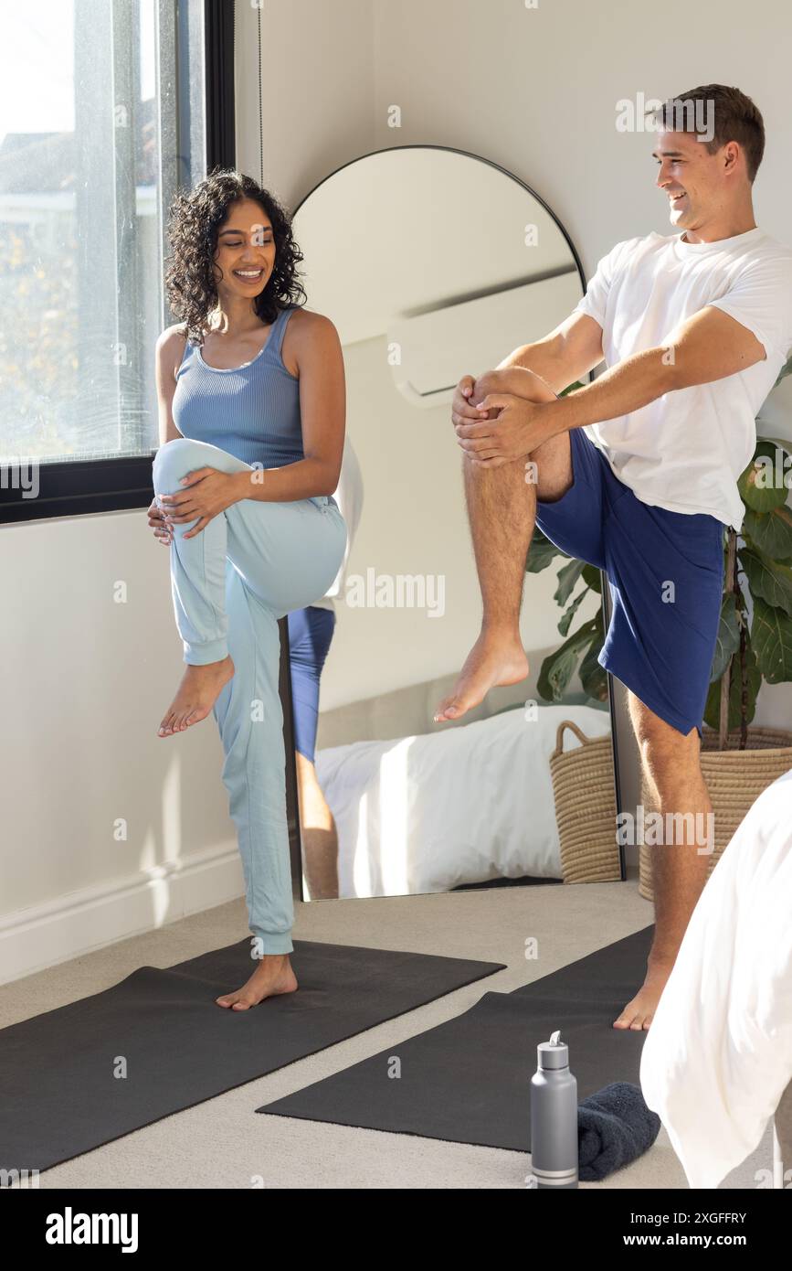 Practicing yoga together, young couple stretching on yoga mats in ...