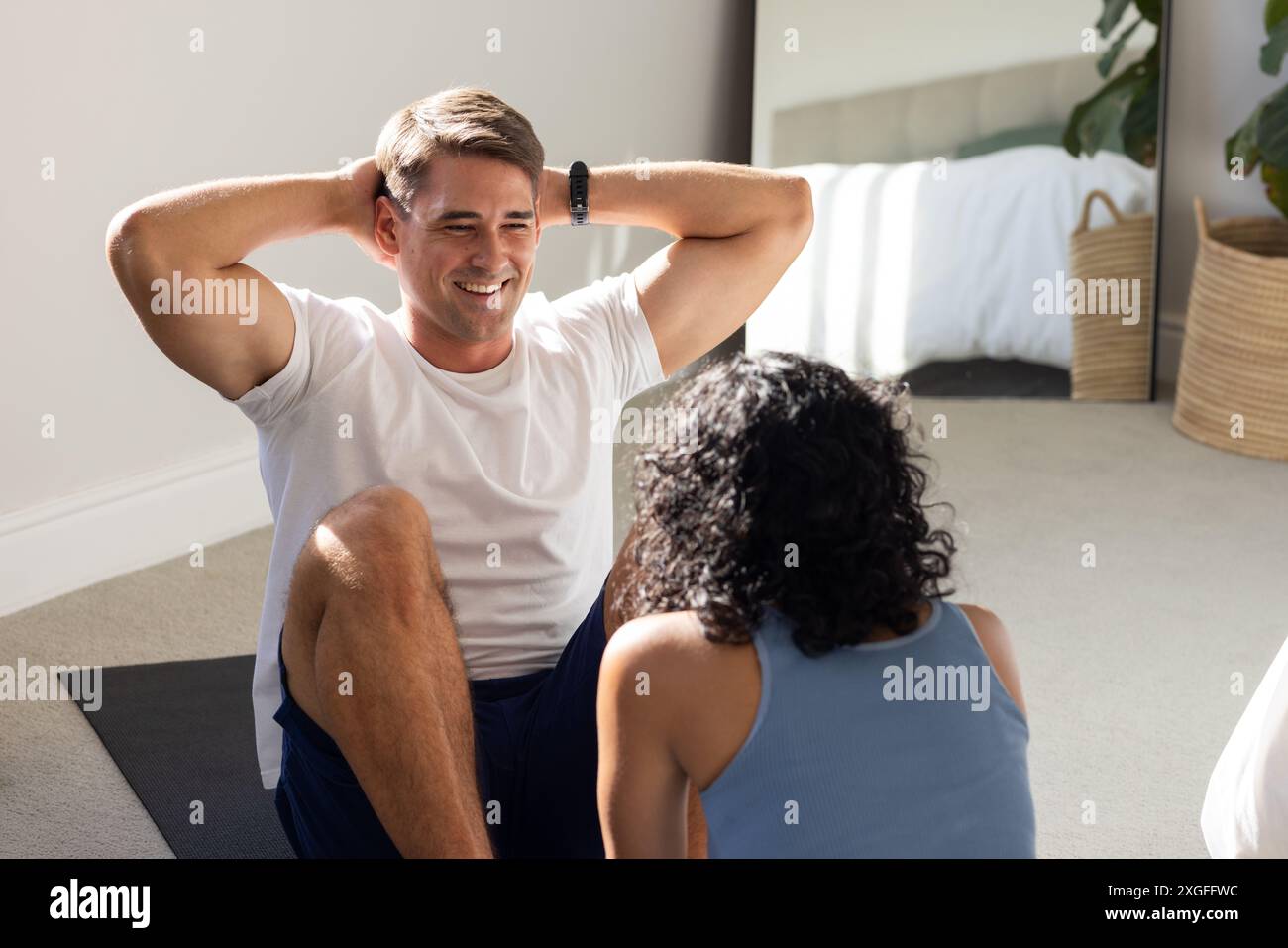 Exercising together, couple doing sit-ups on yoga mat in bedroom ...