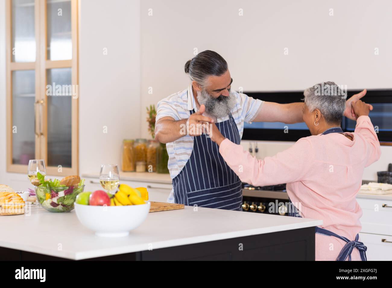 Dancing in kitchen, senior couple enjoying time together while cooking ...