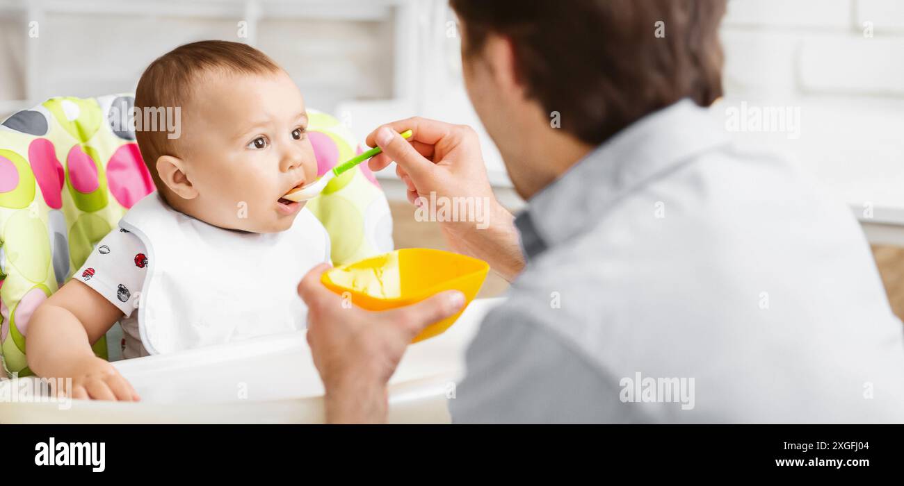 Father Feeding Baby Son In High Chair At Home Stock Photo - Alamy