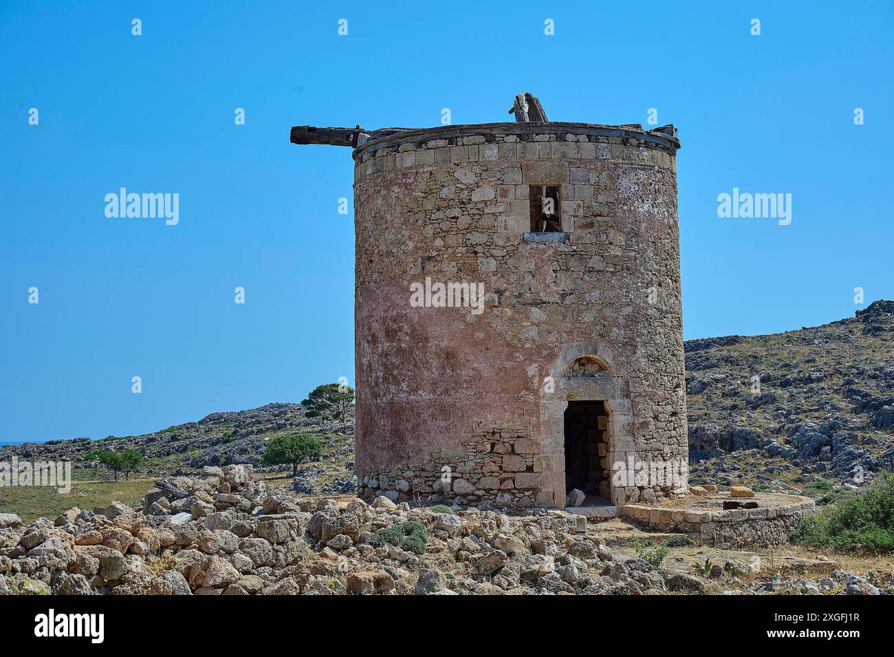 Abandoned old mill on a hill, surrounded by stones, under a clear blue ...