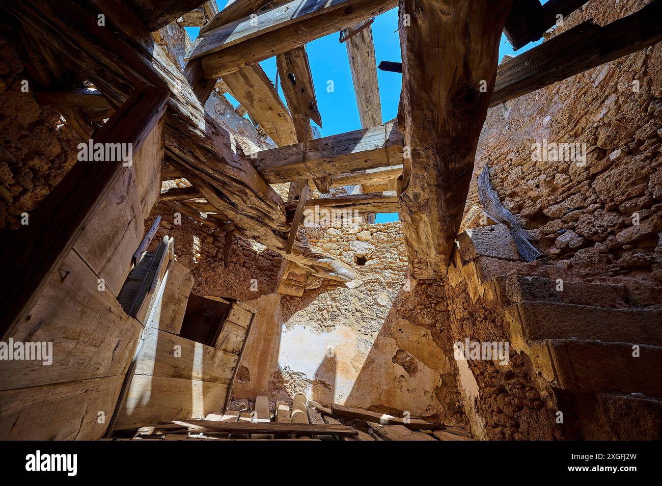 The interior of a crumbling mill with damaged wooden beams and a view ...