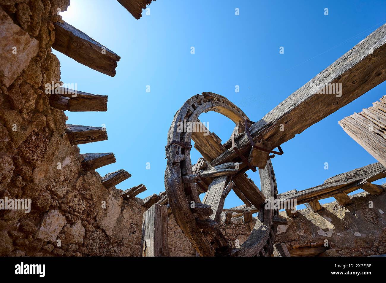 Abandoned building with an old wooden wheel and dilapidated stone walls ...