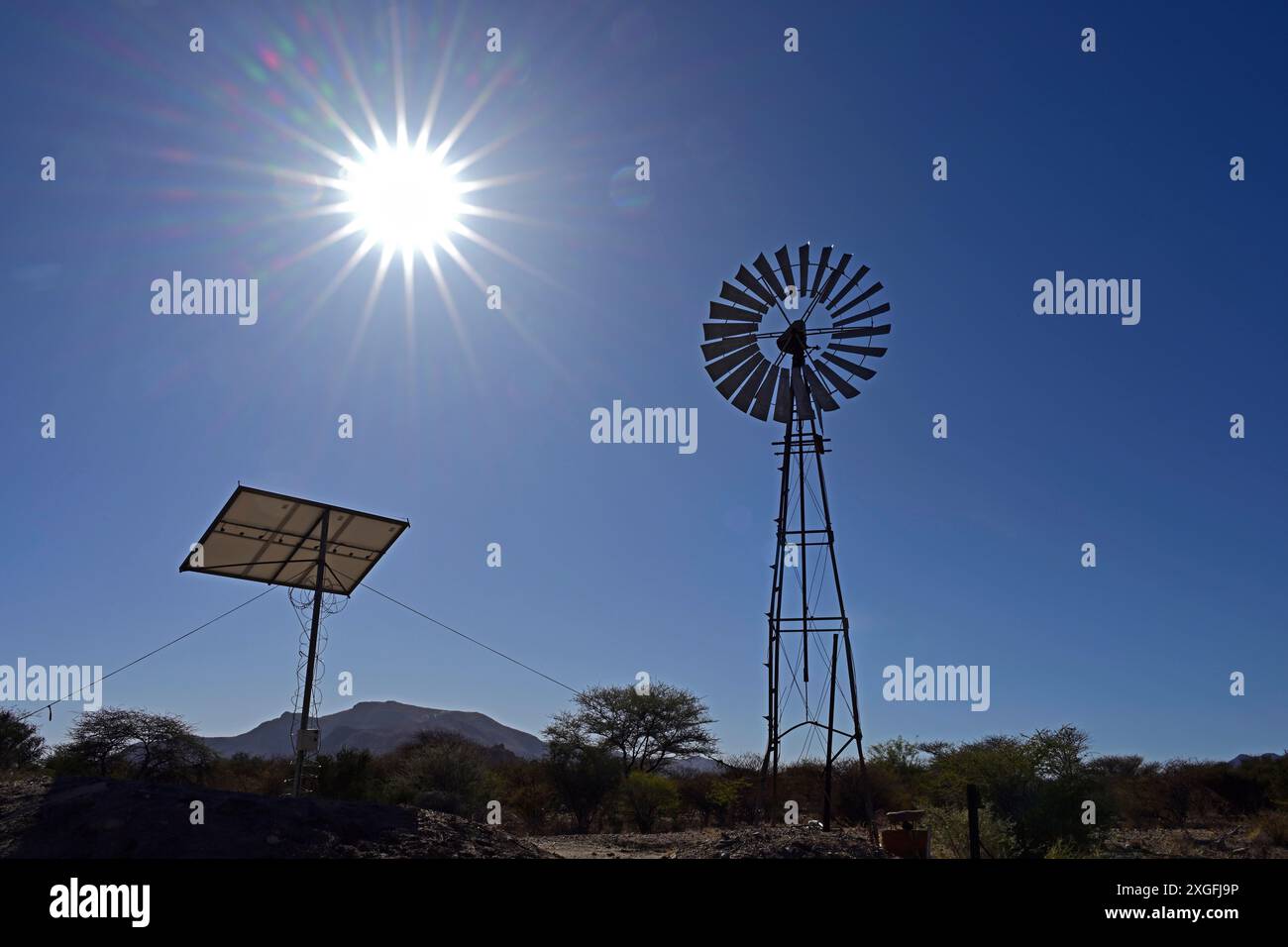 Sun shining from the sky on a solar-powered water pump and wind-powered ...