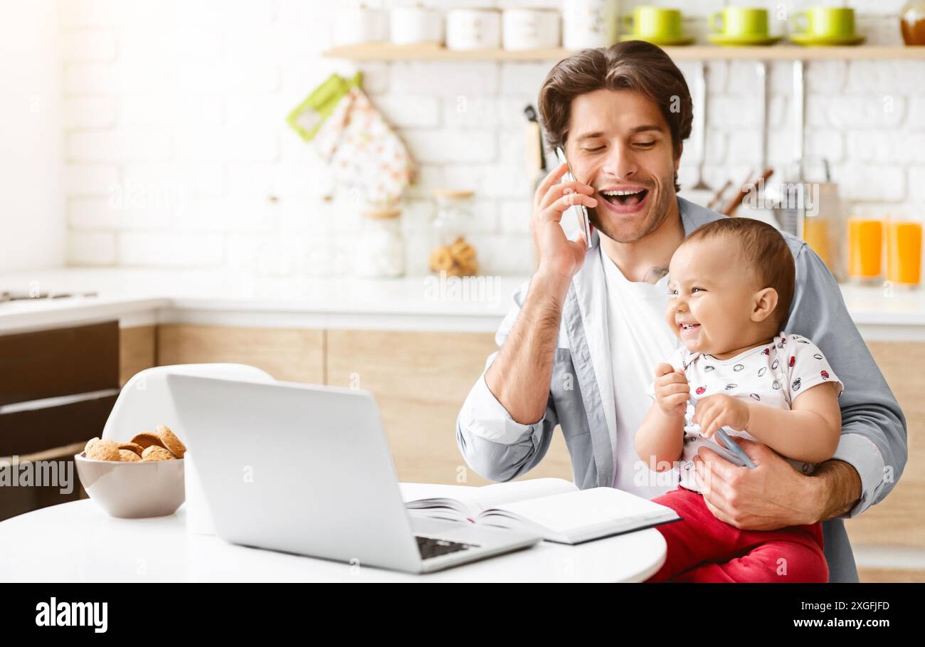Happy Father Talking On Phone While Holding Baby In Kitchen Stock Photo ...