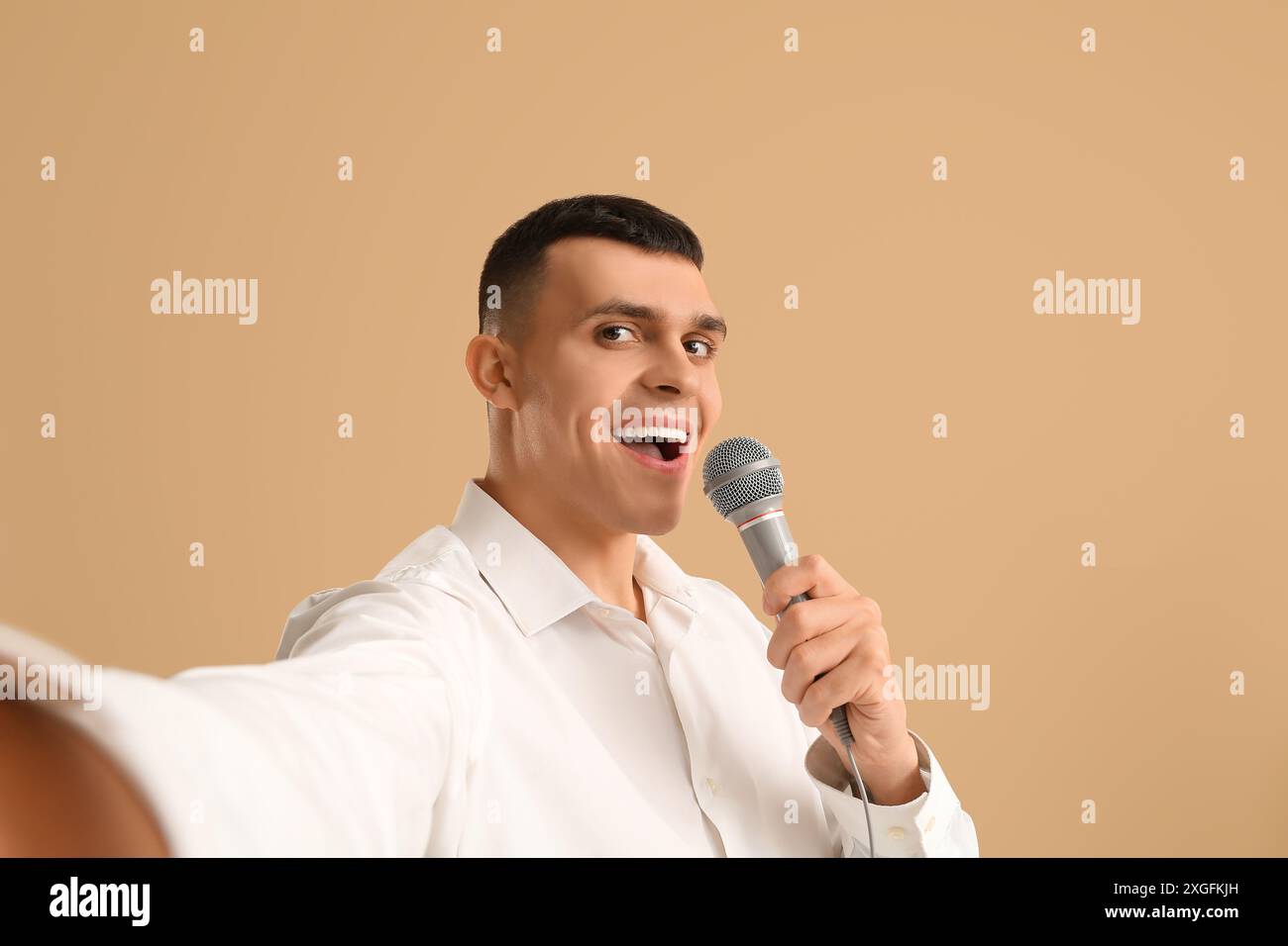 Young man singing with microphone on brown background Stock Photo - Alamy