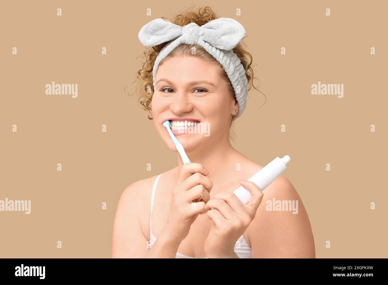 Beautiful young happy woman with tube of toothpaste brushing teeth on ...