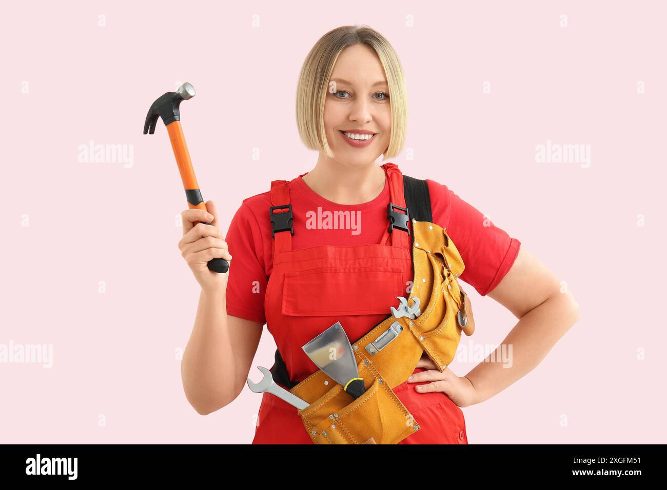 Female worker with tools belt and hammer on pink background Stock Photo ...