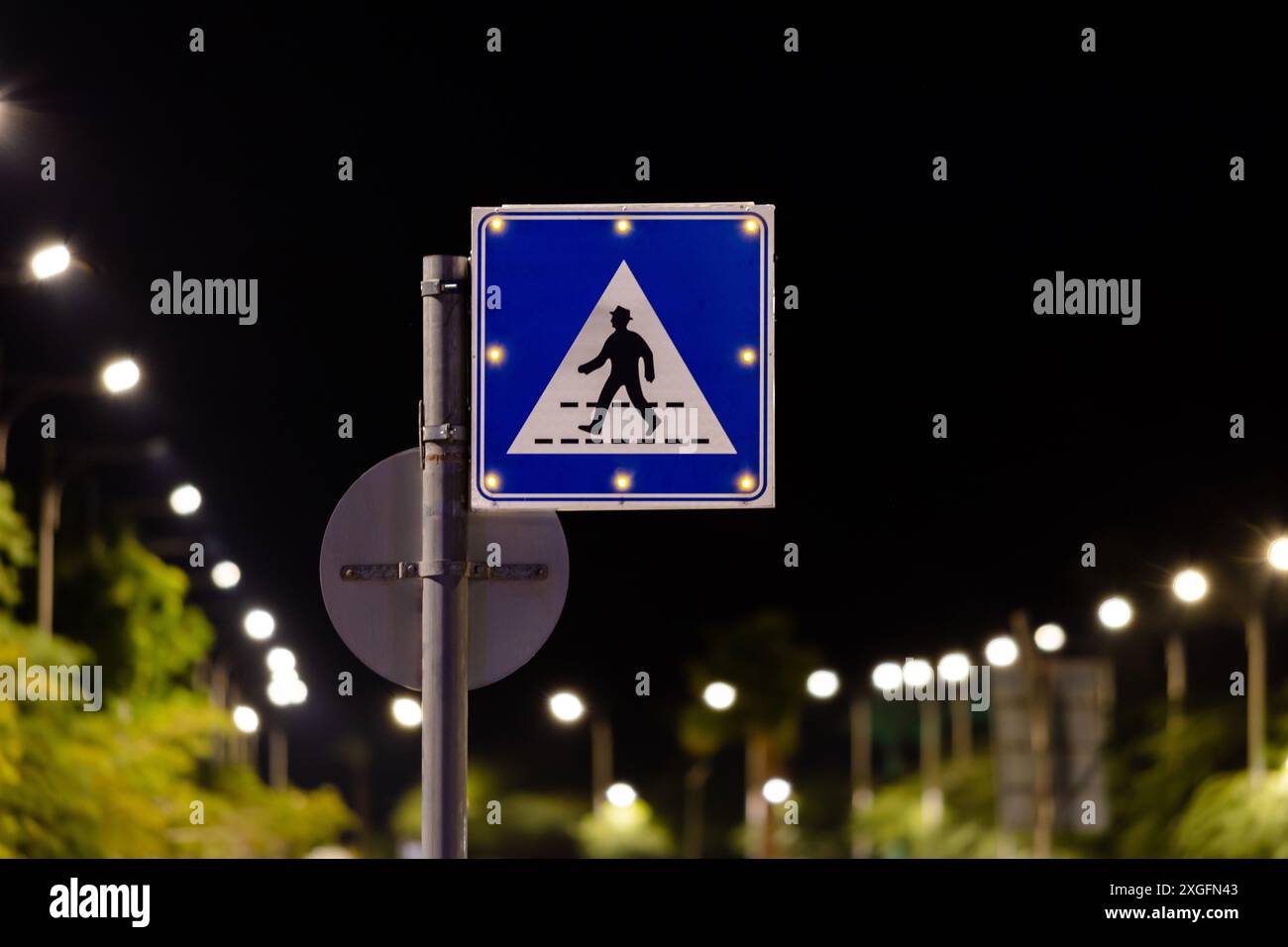 Illuminated pedestrian crossing sign at night. City street lightning ...