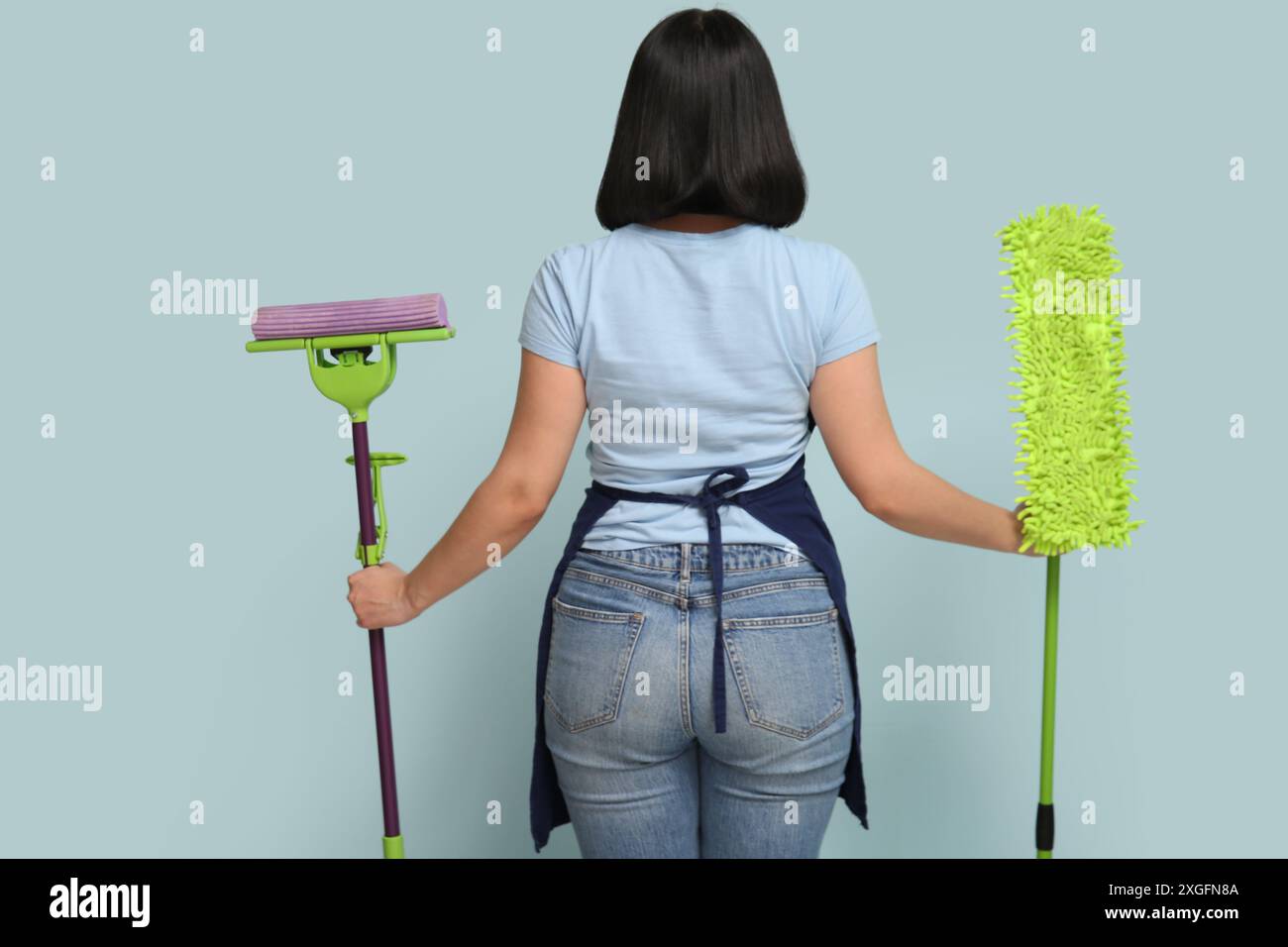 Young woman with floor mops on blue background, back view Stock Photo ...