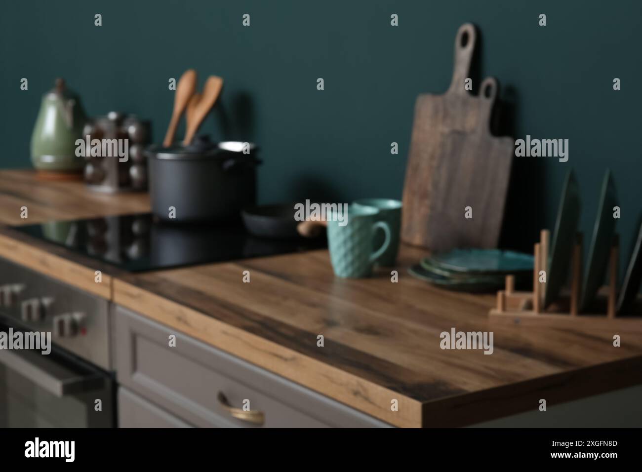 Blurred view of modern kitchen with grey counters, stove and utensils ...