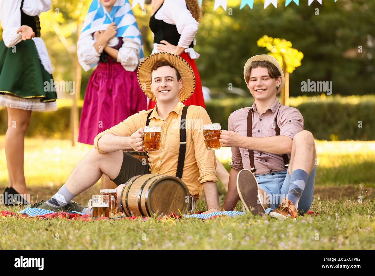 Young men in traditional German clothes with beer outdoors. Octoberfest ...