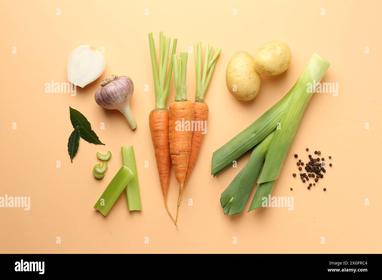 Fresh ripe carrots, vegetables and spices on pale orange background ...