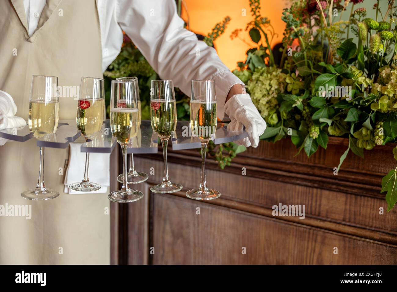 Waiter serving champagne with raspberries on a tray. Catering concept ...