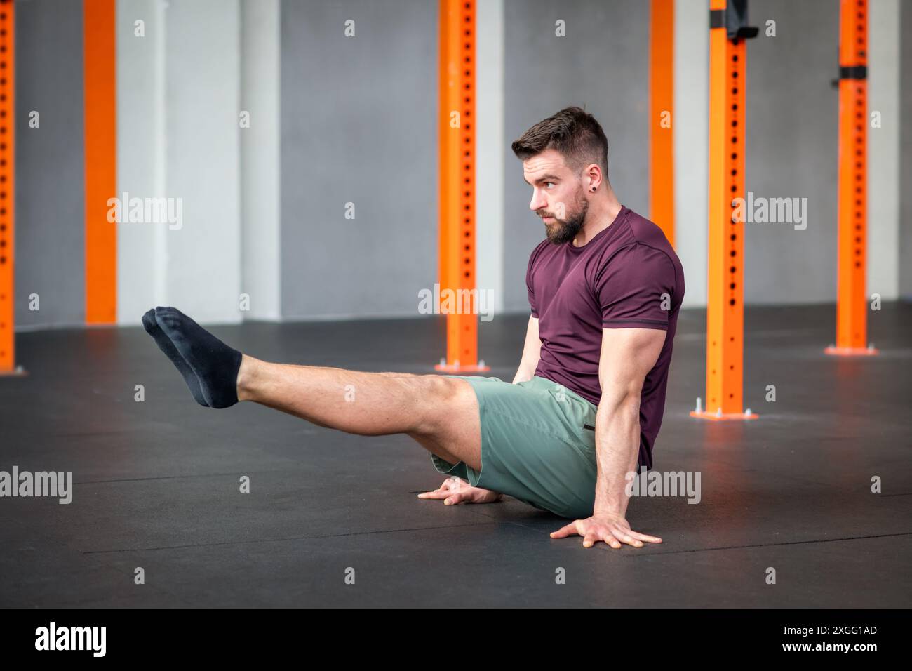 Full body of determined young male in activewear stretching legs while ...