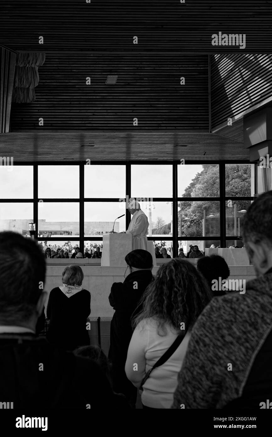 Mature priest leads mass in the chapel of apparitions, viewed from a ...