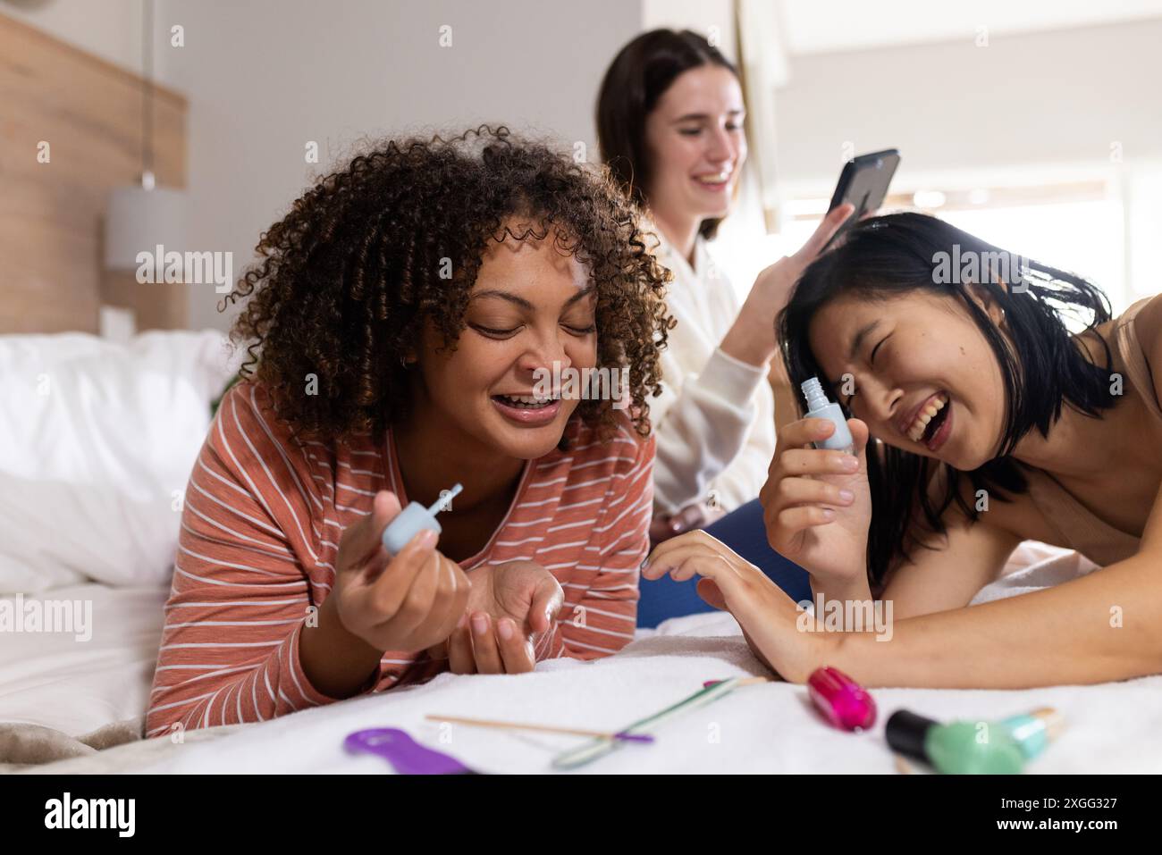 Painting nails and laughing, three women friends enjoying time together ...