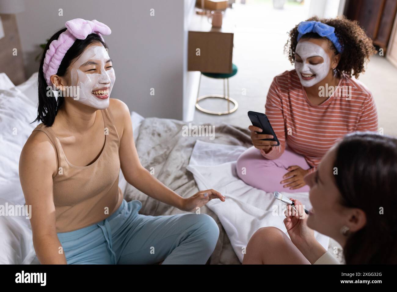 Applying face masks, three women friends relaxing and enjoying spa day ...