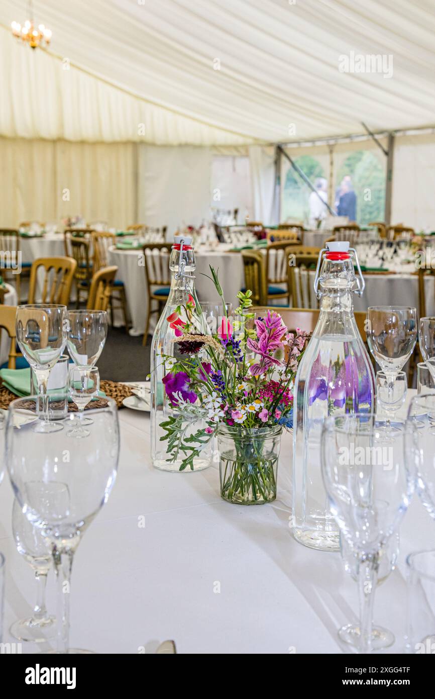 tables with glasses and flowers set up in a marquee for a party Stock ...
