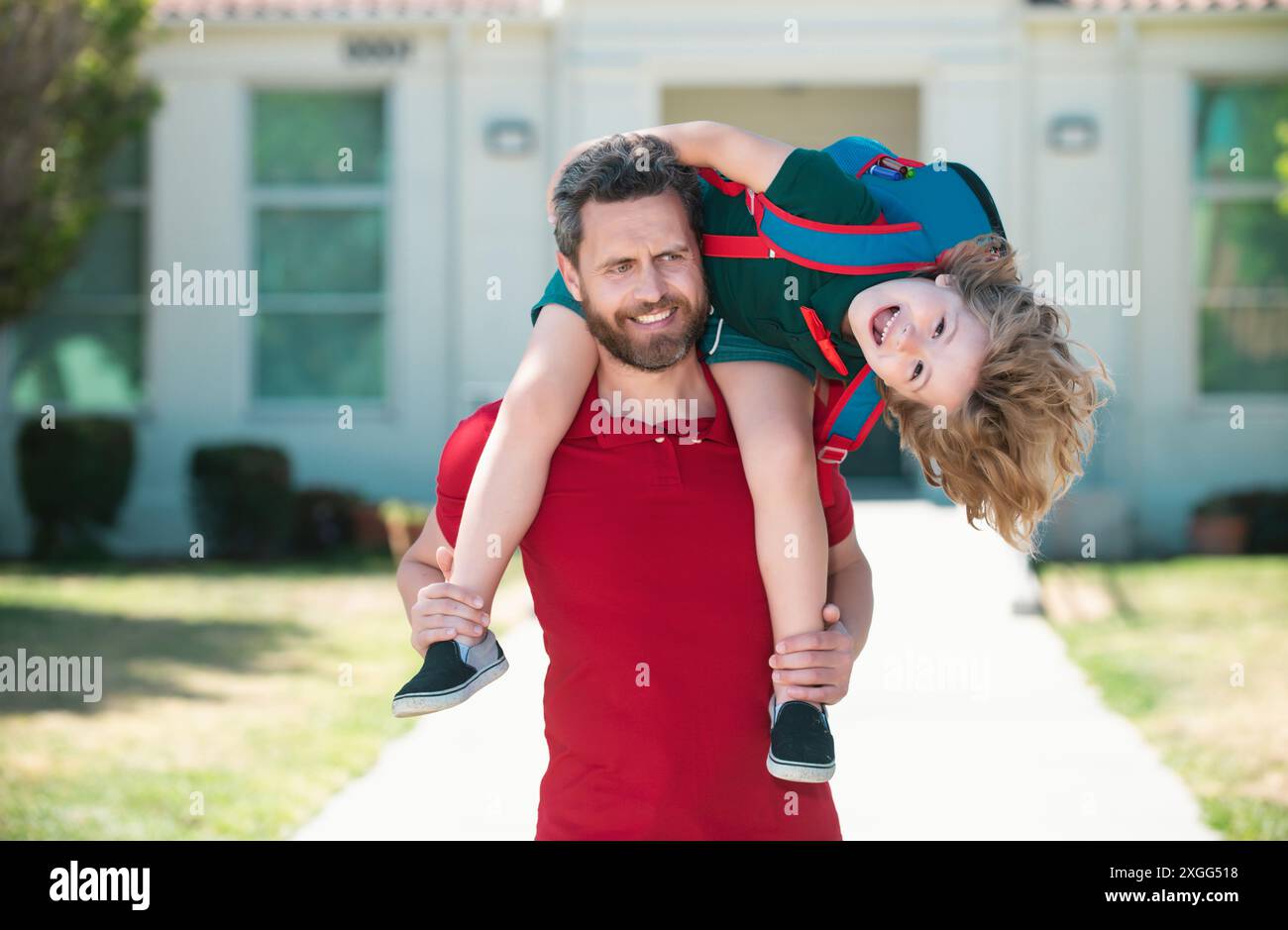 School boy going to school with father. Man giving son piggyback ride after come back from ...
