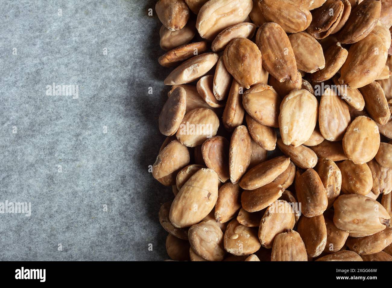 Close-up of roasted blanched almonds on parchment paper background with ...