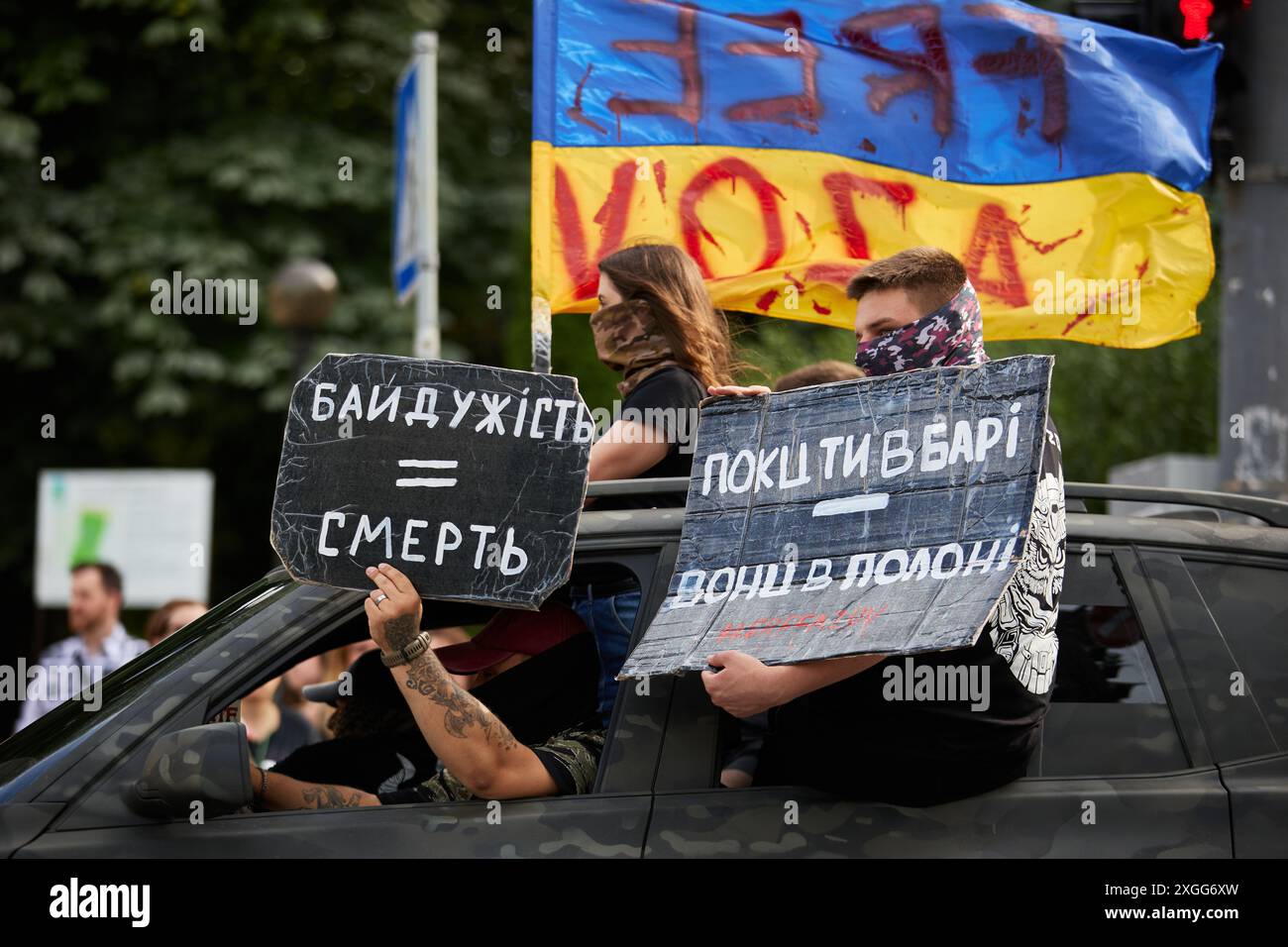 Ukrainian activists ride in a car with banners "Indifference Is Death ...