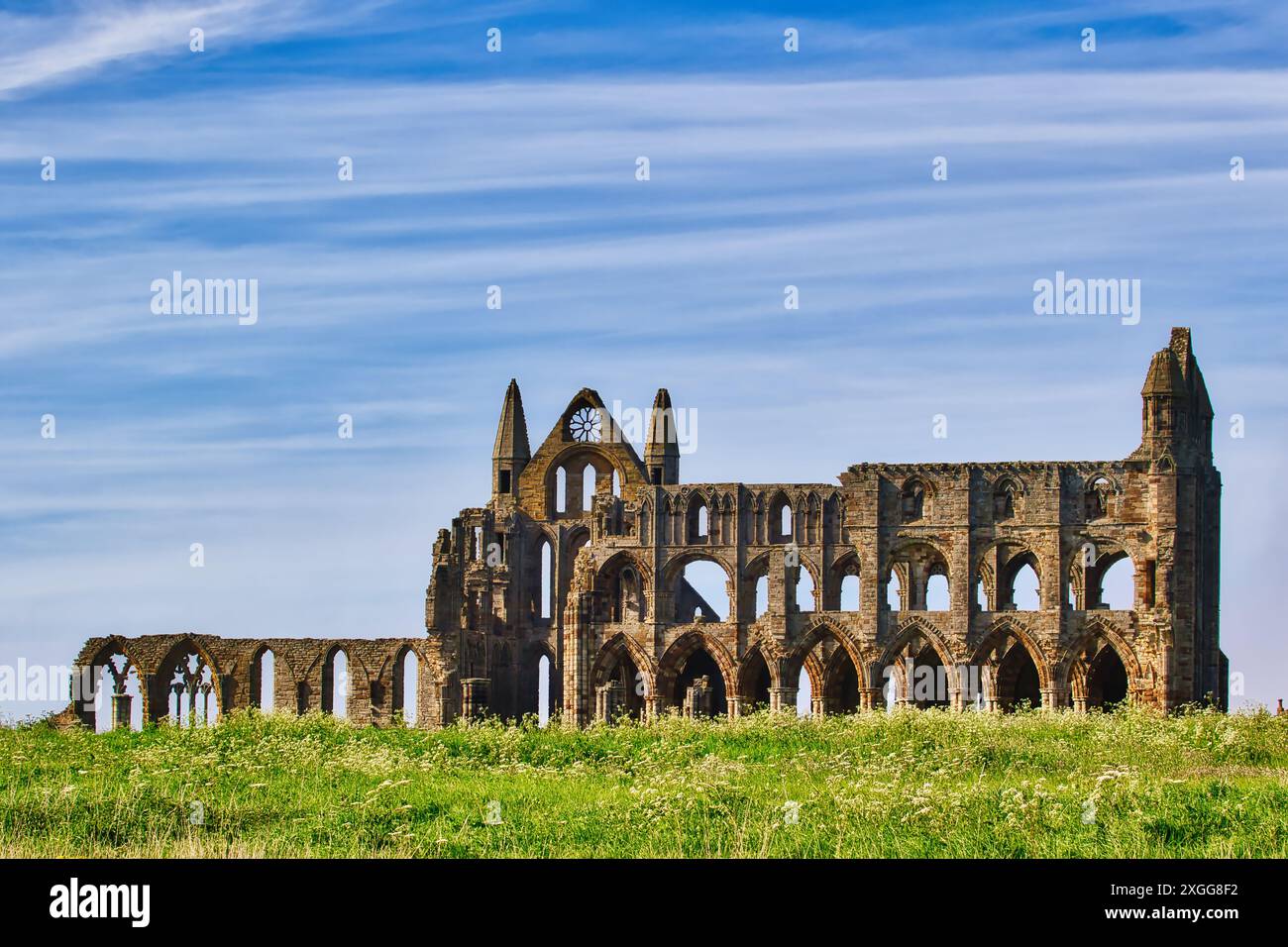 Ruins of an ancient abbey with arched windows and walls, against a blue ...