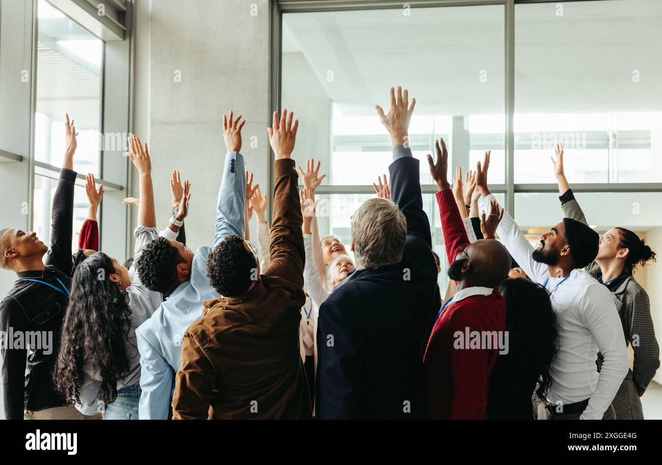 Diverse group of people showing excitement and teamwork by raising ...