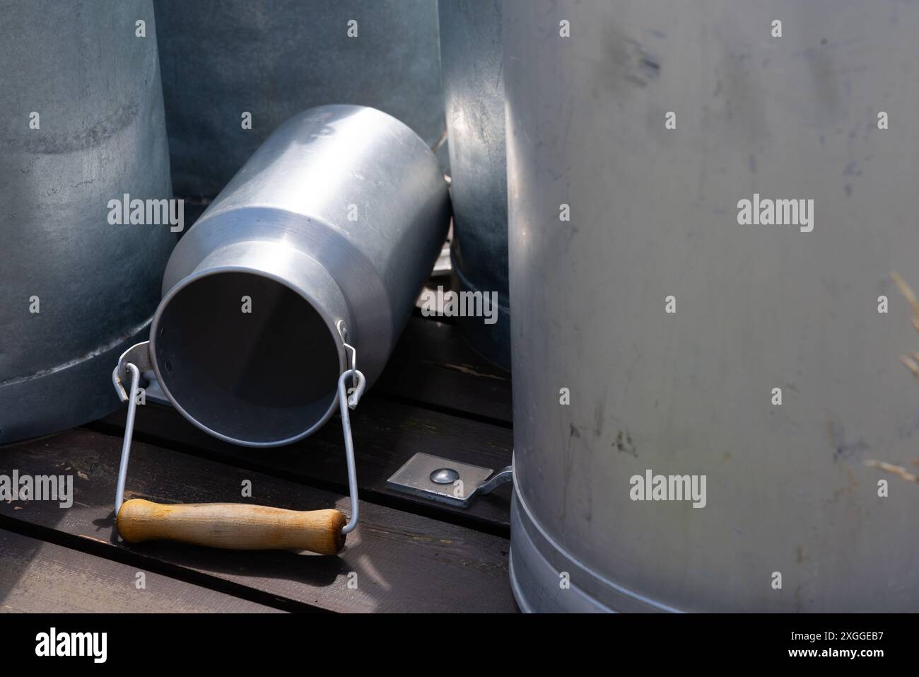 A single aluminum milk can, tilted on its side, rests on a wooden ...