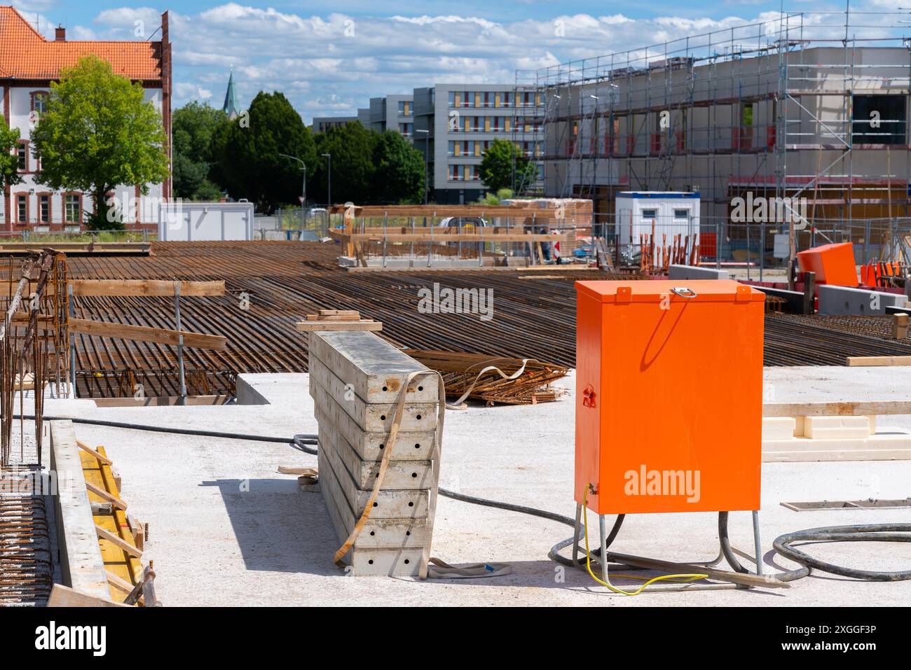 A construction site with an orange electrical box, rebar, and concrete ...