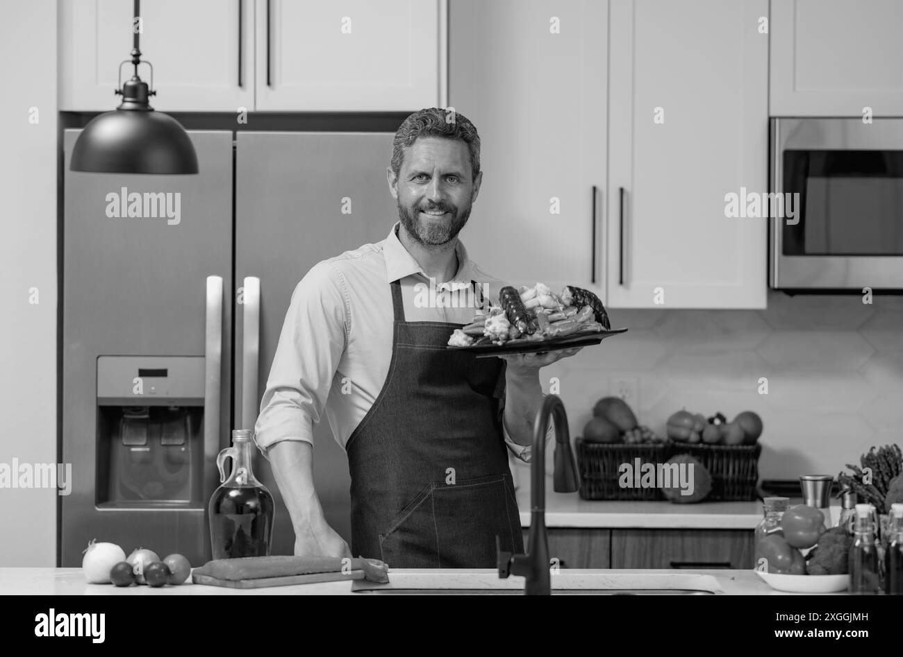 Happy man in cook apron cooking seafood in kitchen. Portrait of middle ...