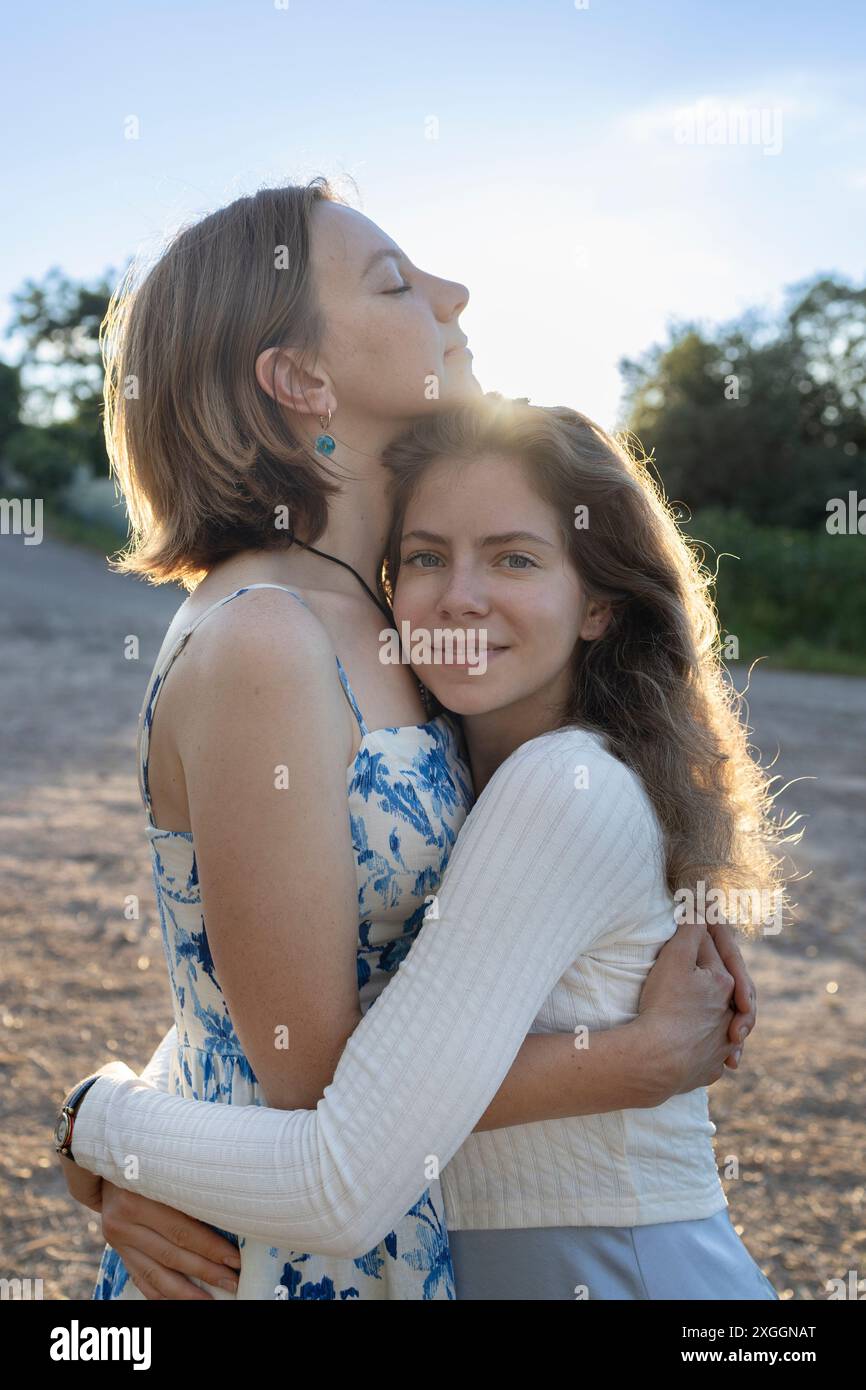 happy mother over 40 and her adult daughter hugging tenderly in the rays of backlight. a family ...