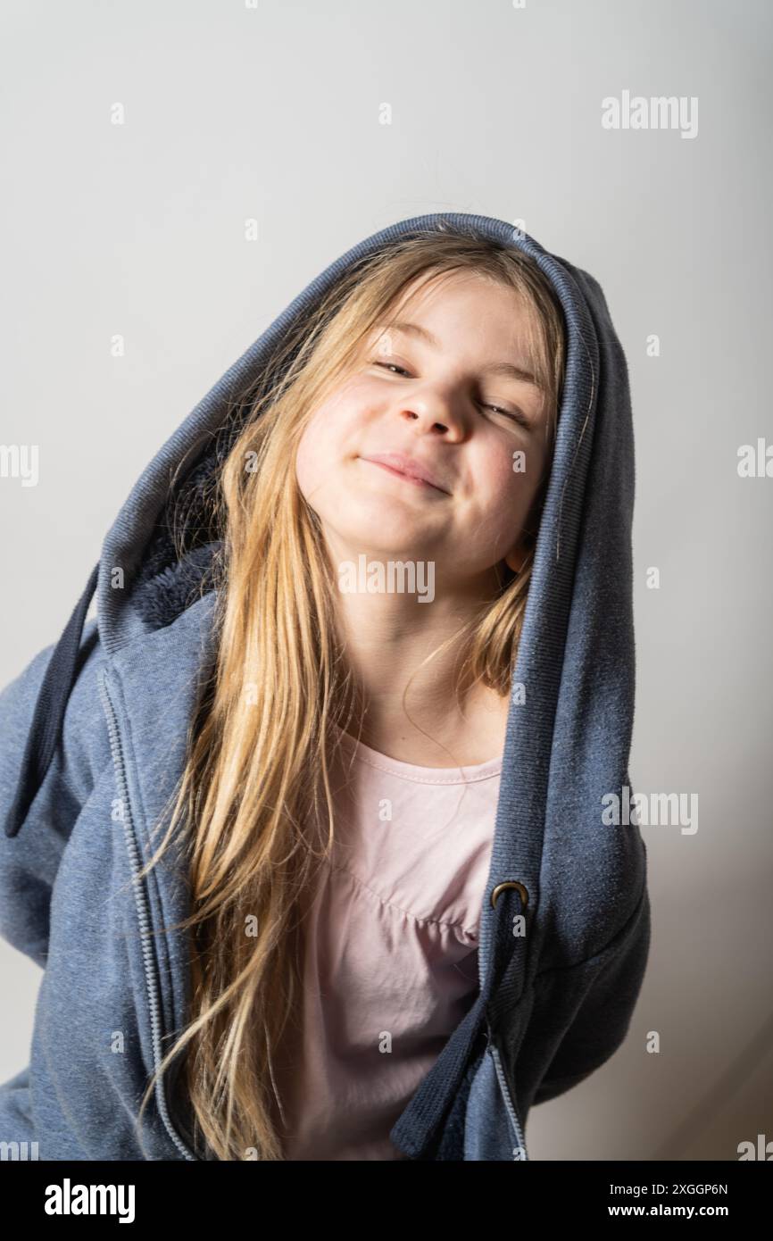 The young girl likes to dance in a gray jacket. Her long, blonde hair ...