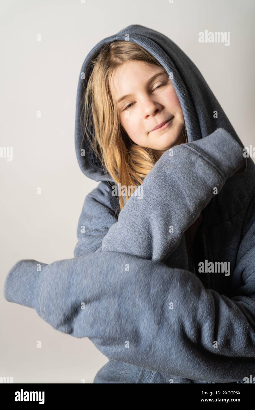 The young girl likes to dance in a gray jacket. Her long, blonde hair ...