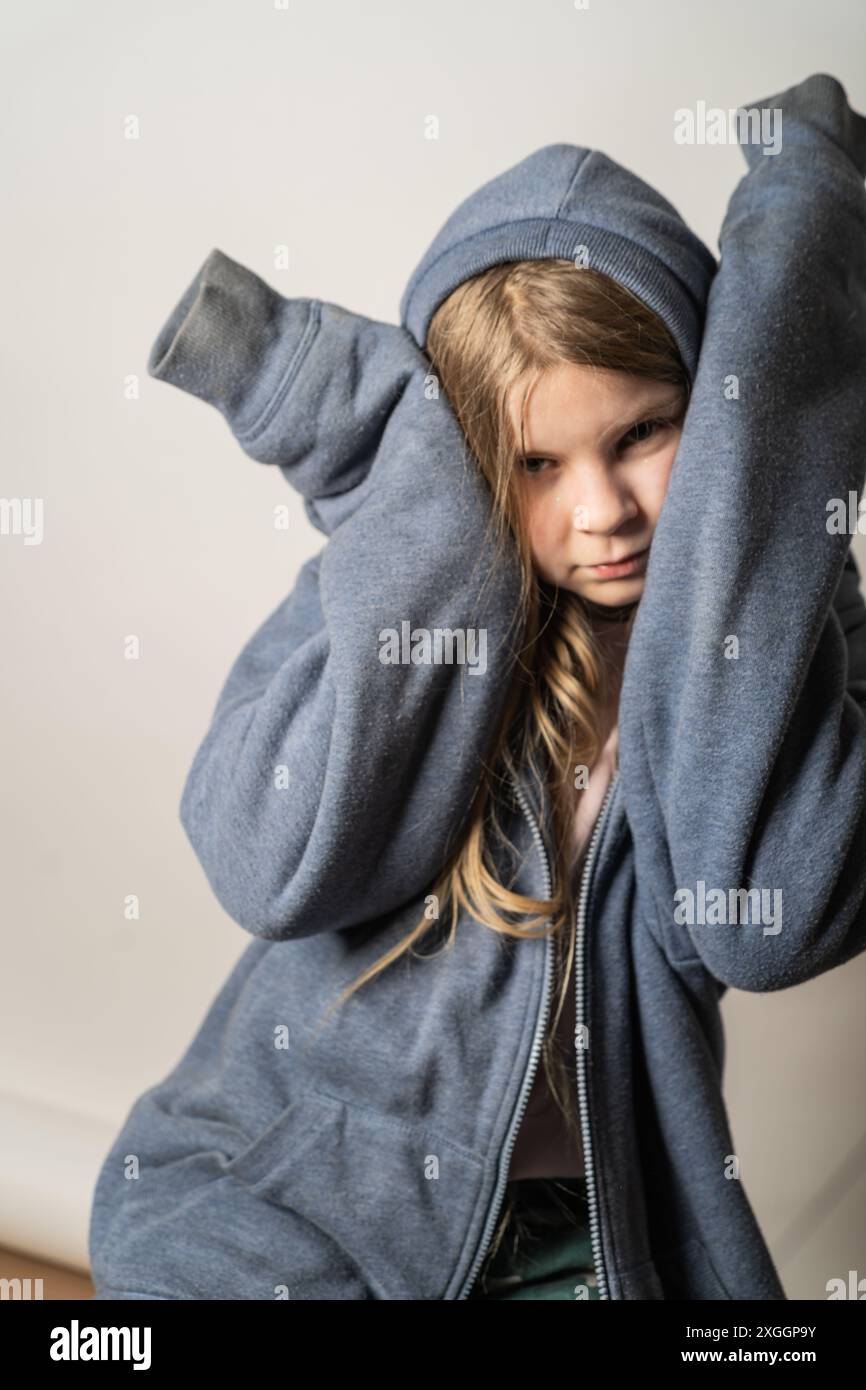 The young girl likes to dance in a gray jacket. Her long, blonde hair ...