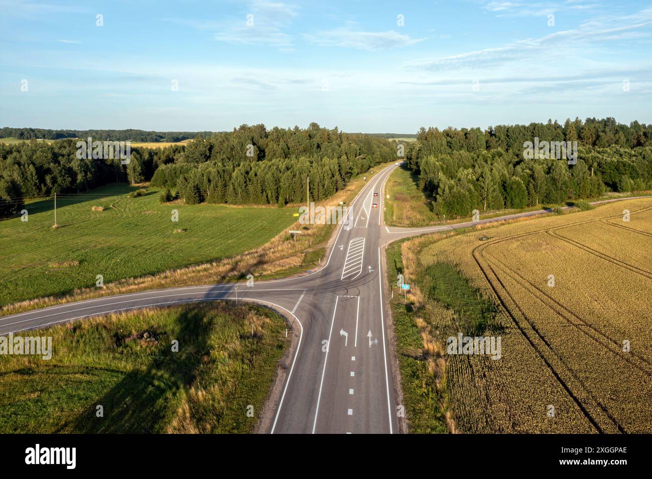 A rural road intersection with a car driving on the main road Stock ...