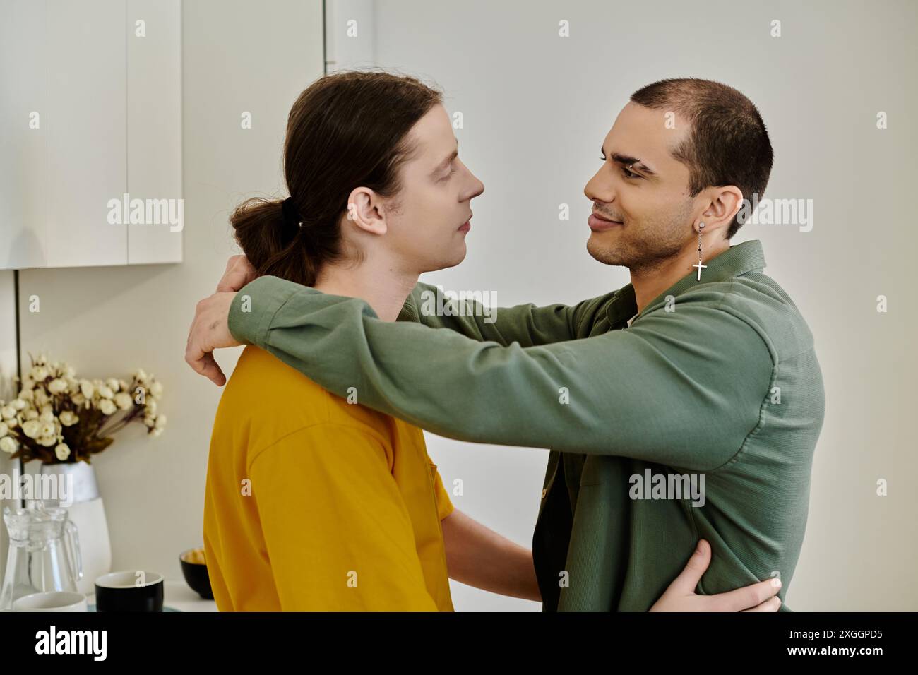 A young gay couple embraces in a modern apartment, showcasing their ...