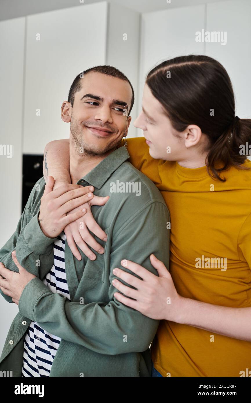 Two young men, dressed casually, share a tender moment in their modern ...